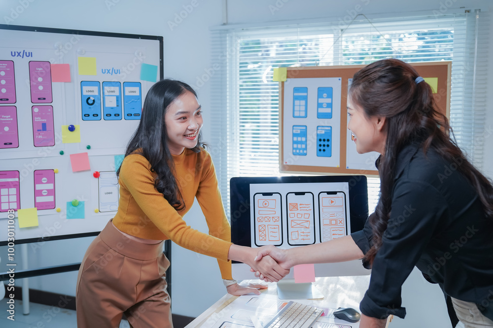 Two Young Asian Women Both Ui Ux Designers Happily Collaborating On A Mobile App Interface In