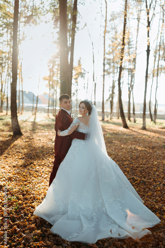 A bride and groom are posing for a picture in a forest. The bride is ...