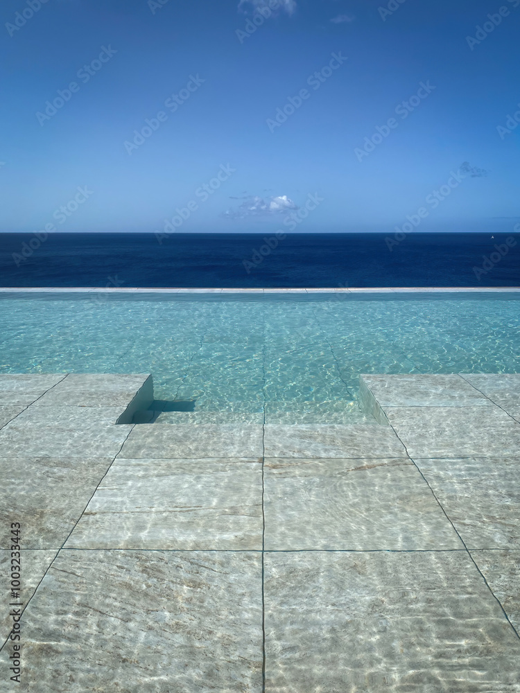 Turquoise colored water of a swimming pool infront of blue water of ...