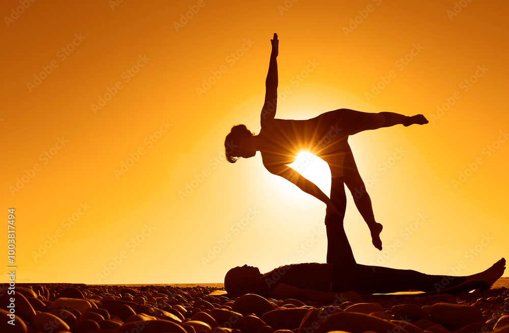 Silhouette of fit sporty couple practicing acrobatic yoga with partner ...