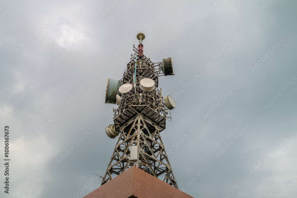 A tall telecommunications tower stands against a blue sky and fluffy ...