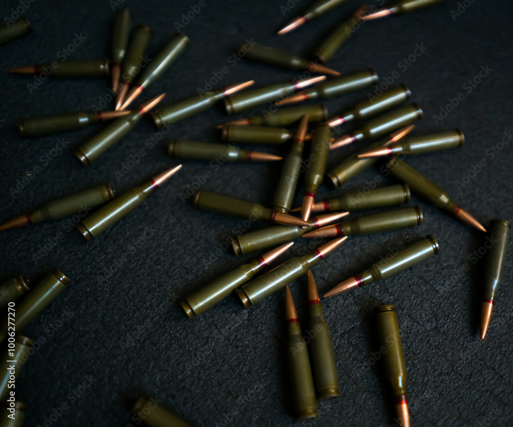 Scattered on a dark surface are bullets, cartridges for a kalashnikov ...