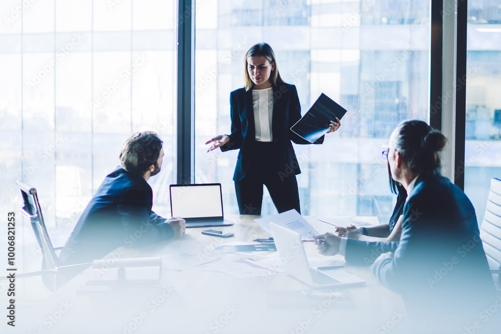 Puzzled female director in elegant suit communicating with employees ...