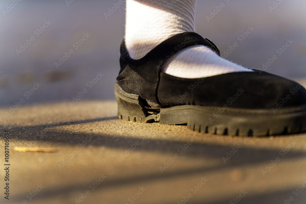 stark contrast of elegance and wear, a white sock-clad foot nestles in ...