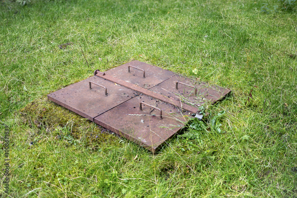 Rusty metal cover with multiple sections and handles over farm water ...