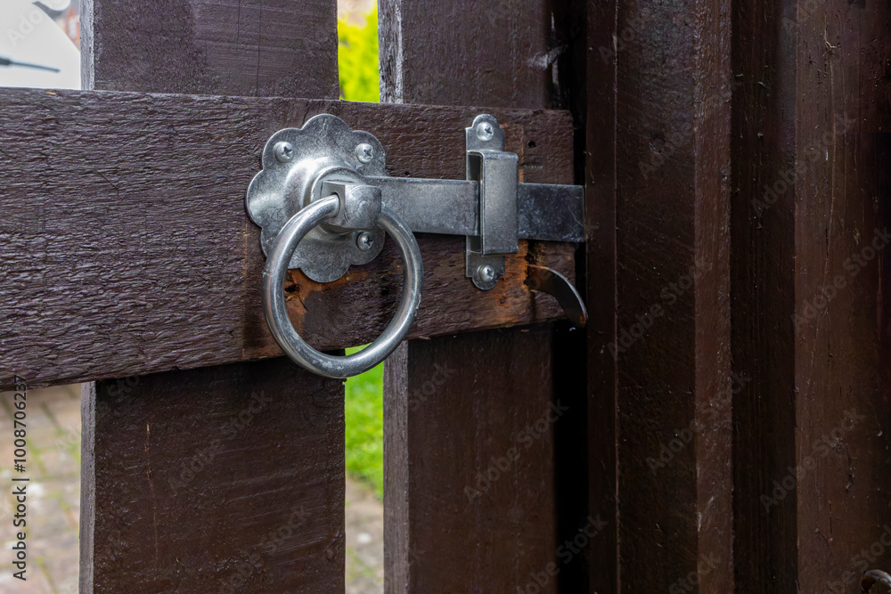 Silver gate latch with a ring handle on brown wooden backyard garden ...