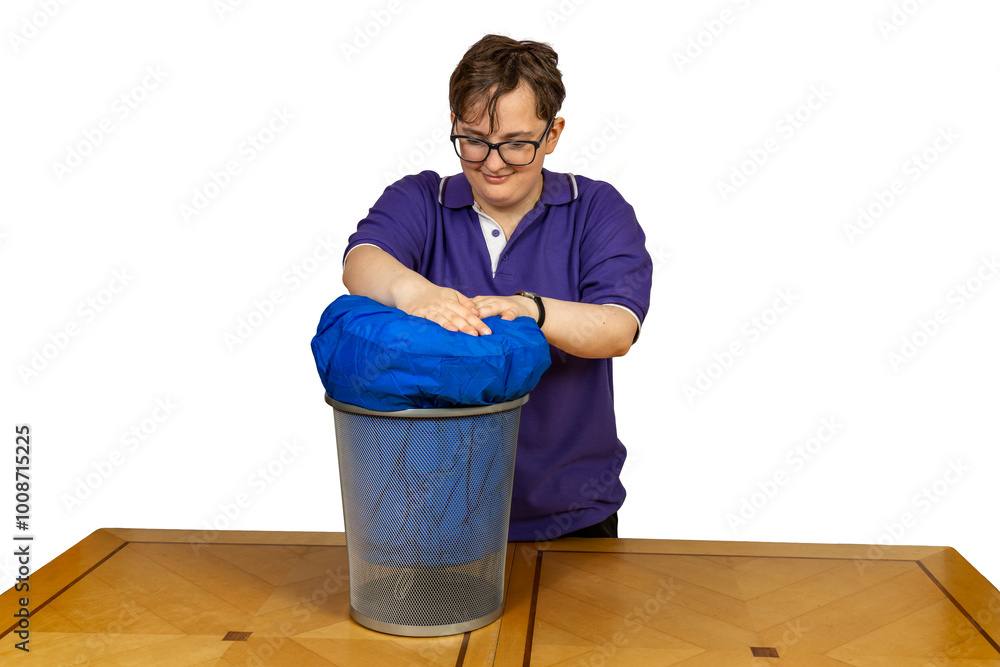 Young student stuffs blue sleeping bag into waster paper trash can bin ...
