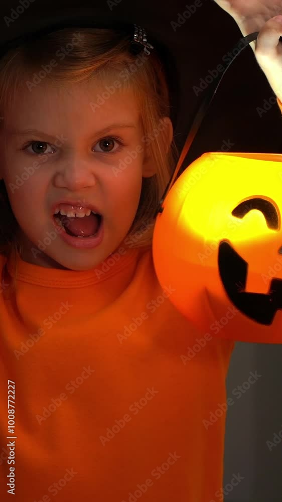 Angry little girl in witch costume fun scares with lantern pumpkin in ...