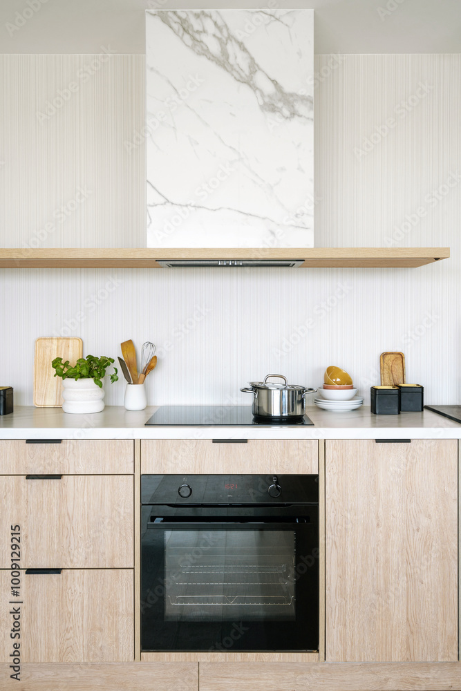 Modern kitchen with marble range hood, electric oven and induction ...