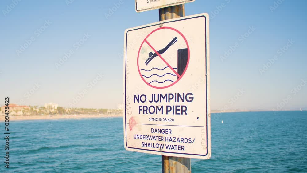 A warning sign on a pier indicating no jumping from the pier due to ...