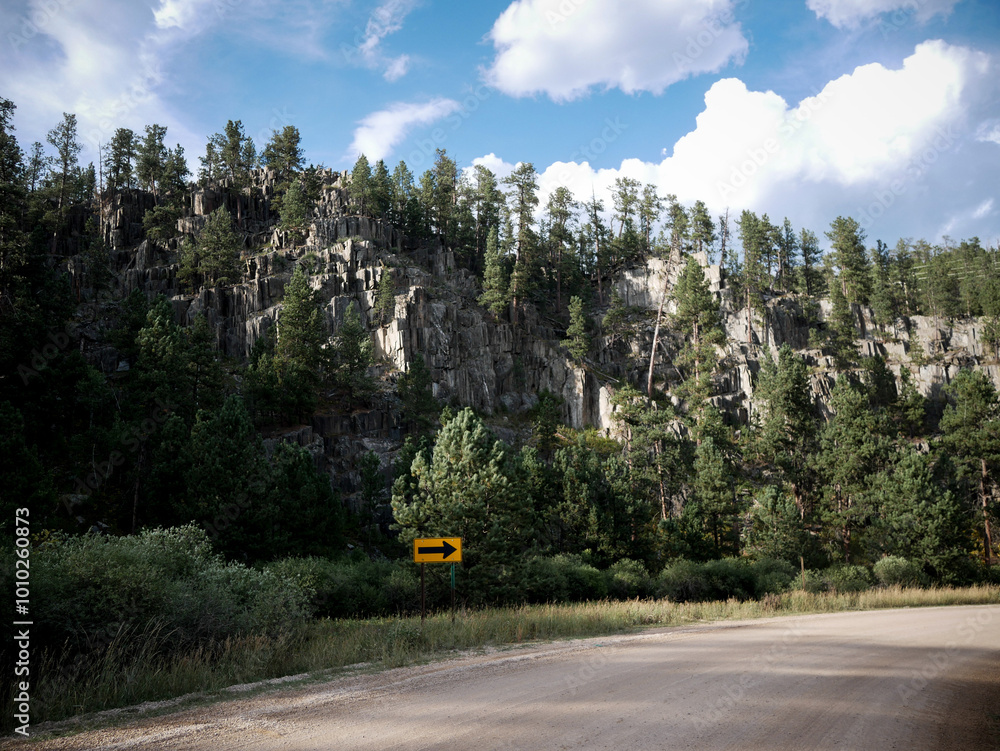 Paved road underneath towering rock cliffs in the Black Hills National ...
