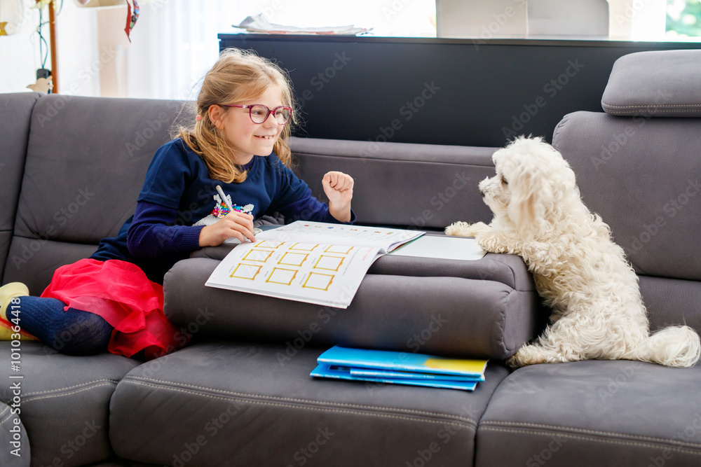 Little young girl with eyeglasses doing school homework. Child writing ...