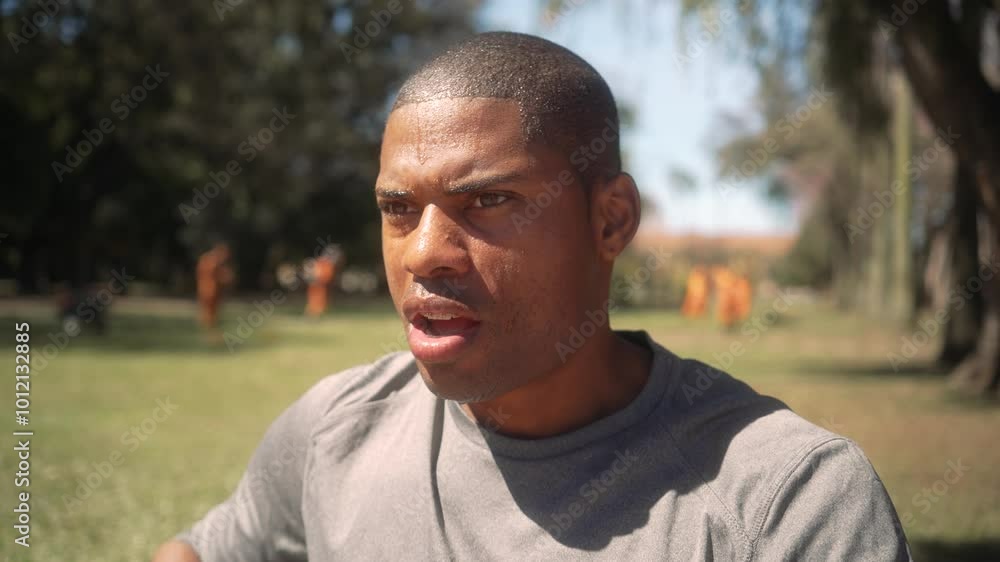Tired African American athlete wiping sweat from his face while resting ...