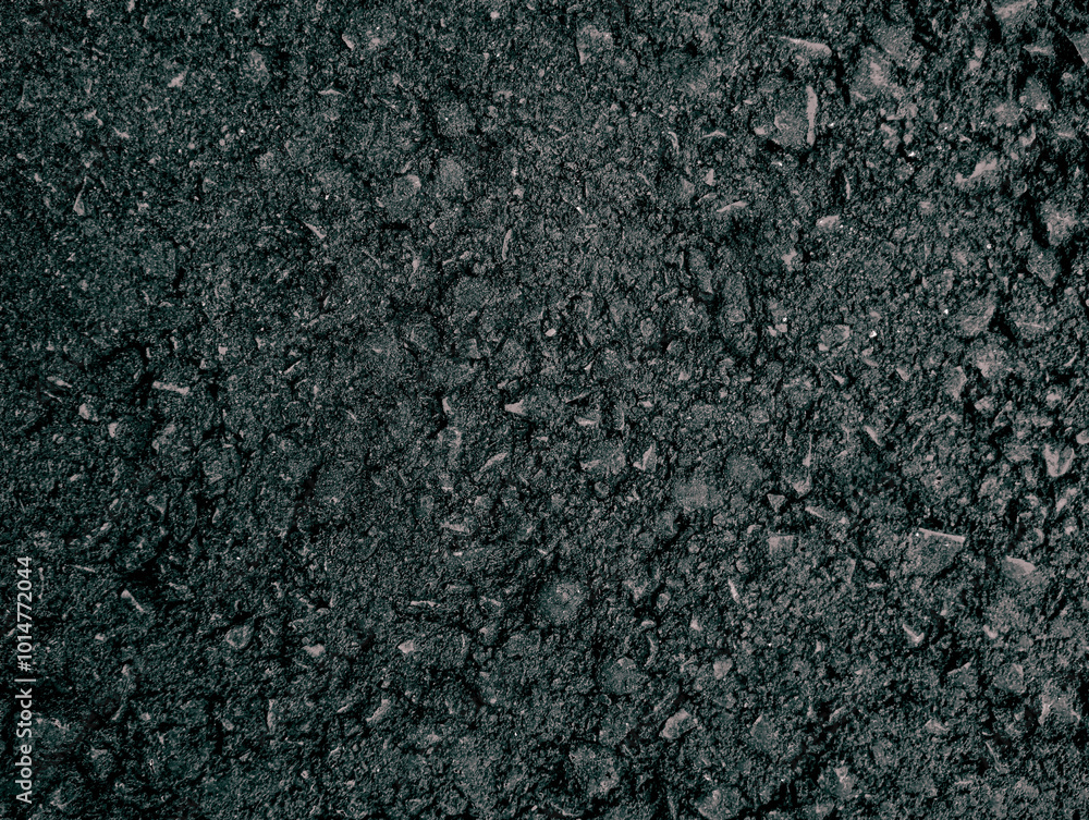Dark asphalt road texture with rough stone granules, providing a ...