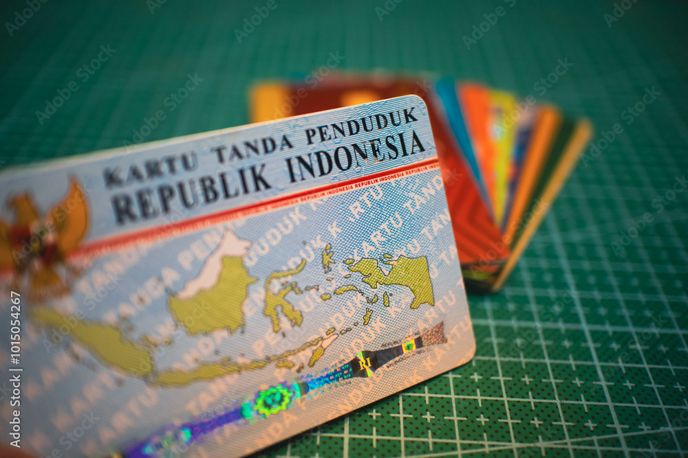 Blue Indonesian ID card (Kartu Tanda Penduduk) close up on a green grid ...