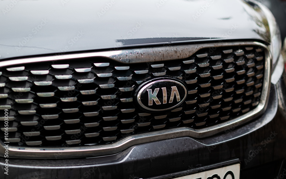 A close-up view of a black Kia car's front grille, showcasing the logo ...