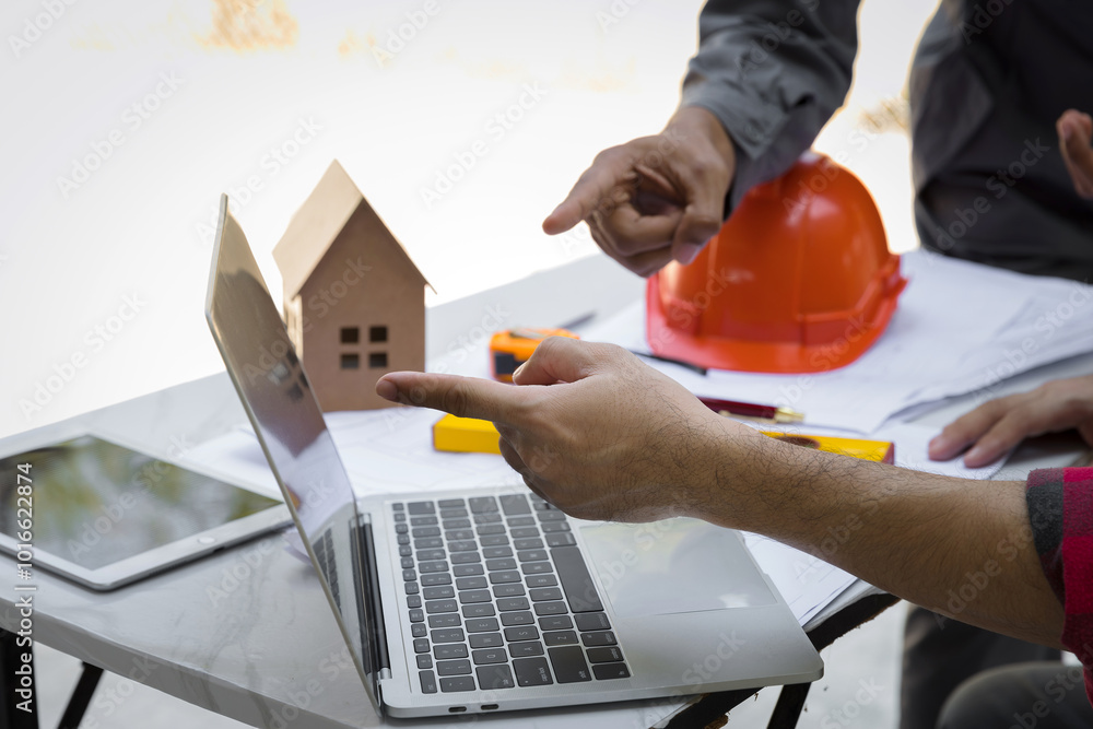 Engineers and architects pointing at laptop screens looking at ...