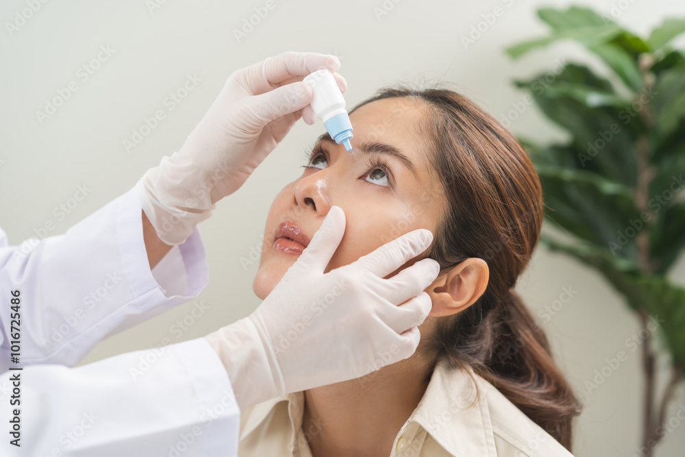 Foto de Health care concept, eye doctor eye drops to asian young woman ...