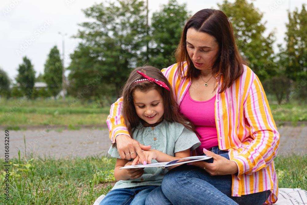 Portrait of a cute girl and her mother reading a book together. Mom ...