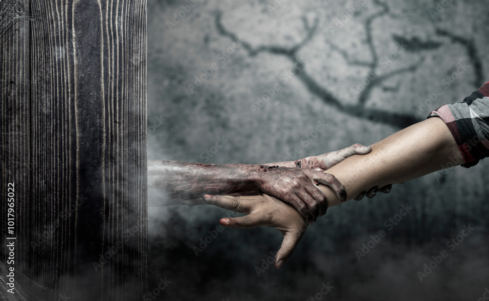 A zombie hand with a bloody wound grabs a human hand in dark room ...