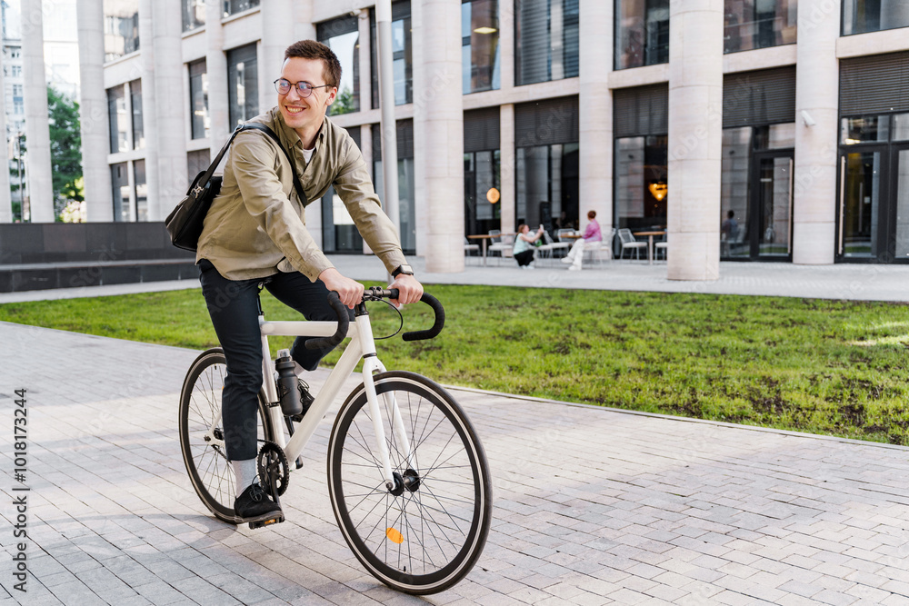 Young Man Cycling on a White Bicycle Through a Modern Urban Plaza With ...