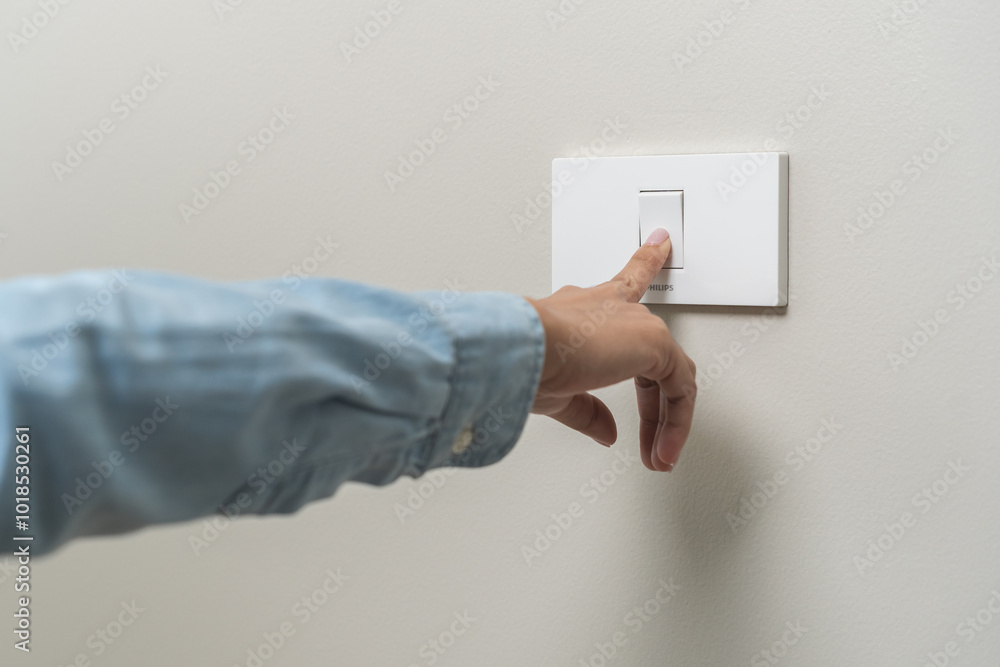 Asian young woman hand turn off on lighting switch at home room. Finger ...