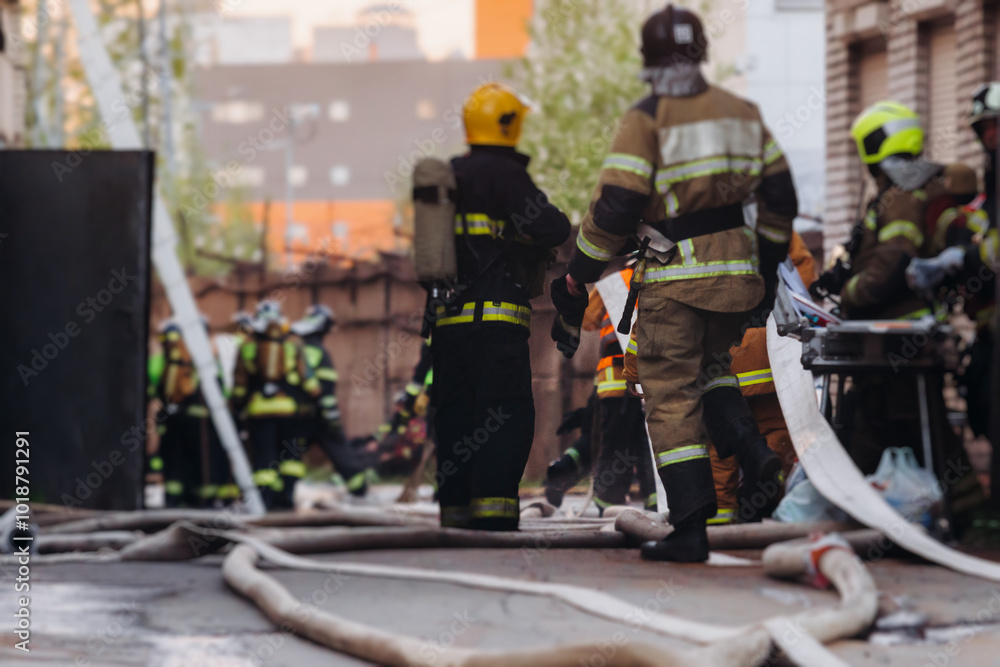 Group of fire men in uniform during fire fighting operation in the city ...