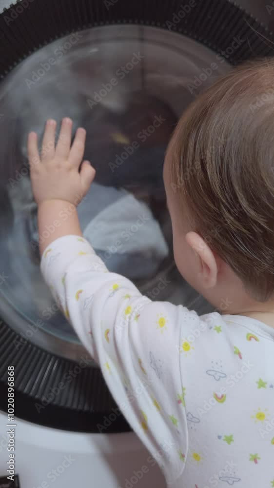 Toddler watching the washing machine spinning around. The image ...