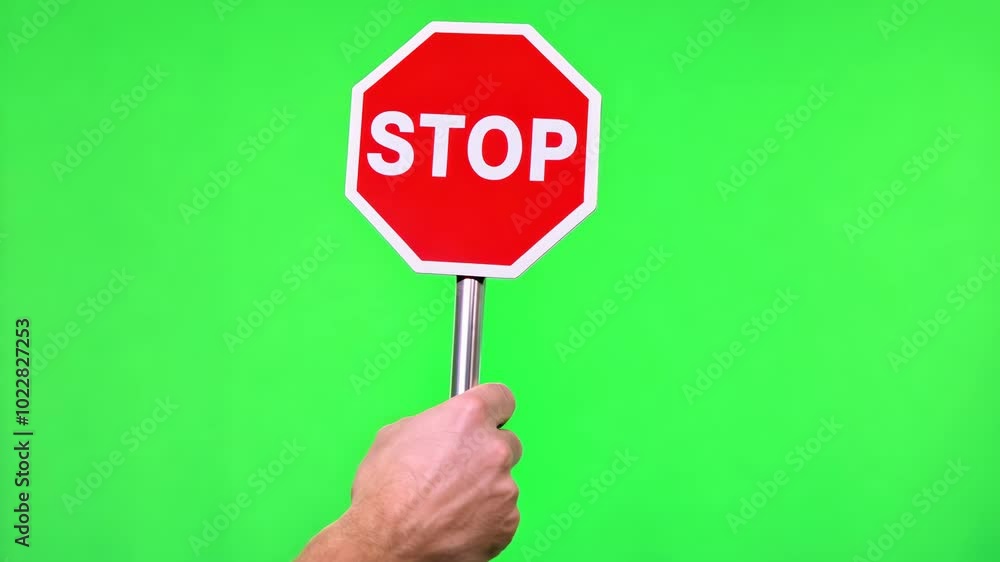 Hand holding red stop sign on green background, caution symbol and ...