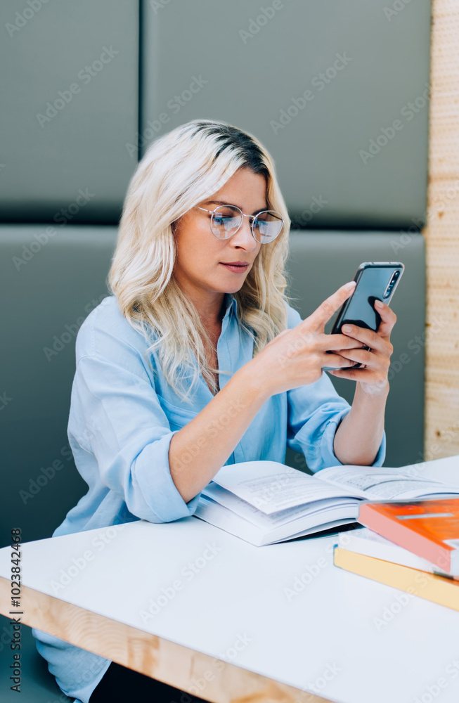Attractive blonde hipster girl using application on smartphone for ...