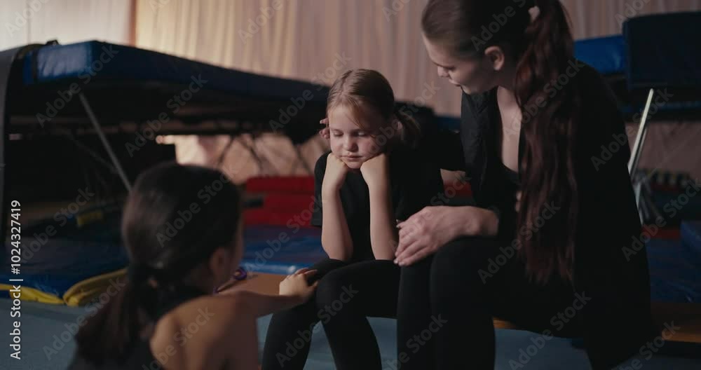 A girl gymnastics coach in a sports uniform supports and consoles her ...