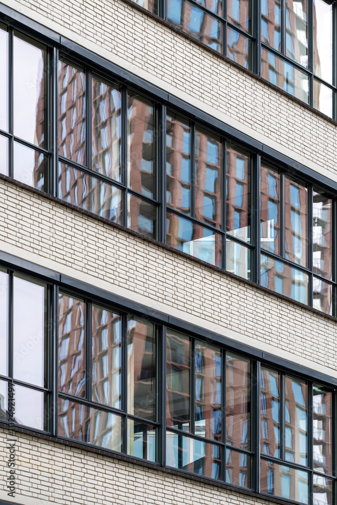 A contemporary building facade boasts rows of reflective glass windows ...