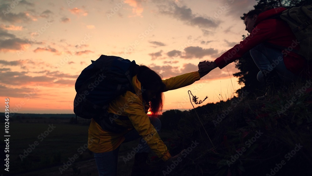 Travelers give each other helping hand, climbing to top of mountain ...