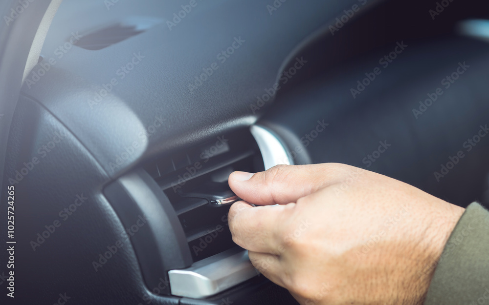 Car owner adjusts the direction of the air vent by hand, ensuring ...