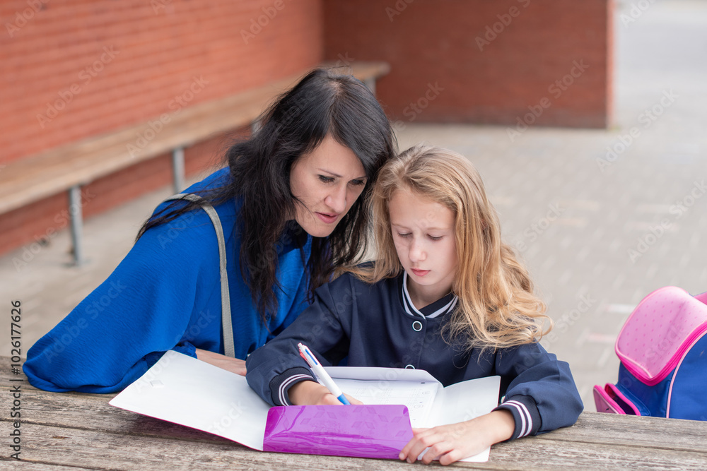 smart girl solving math problems on her own while her mother sits ...