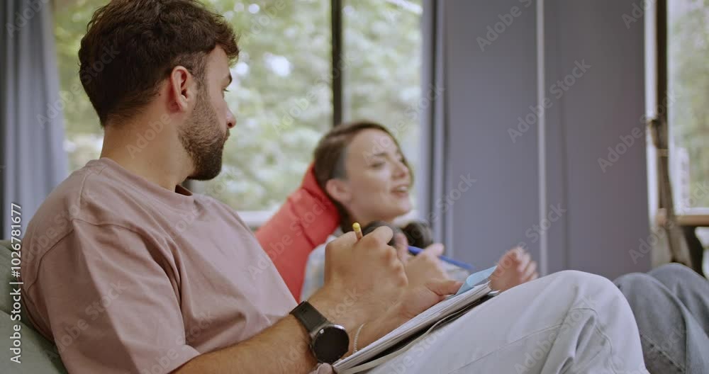 Two young students collaborate on a project in the library, enjoying ...
