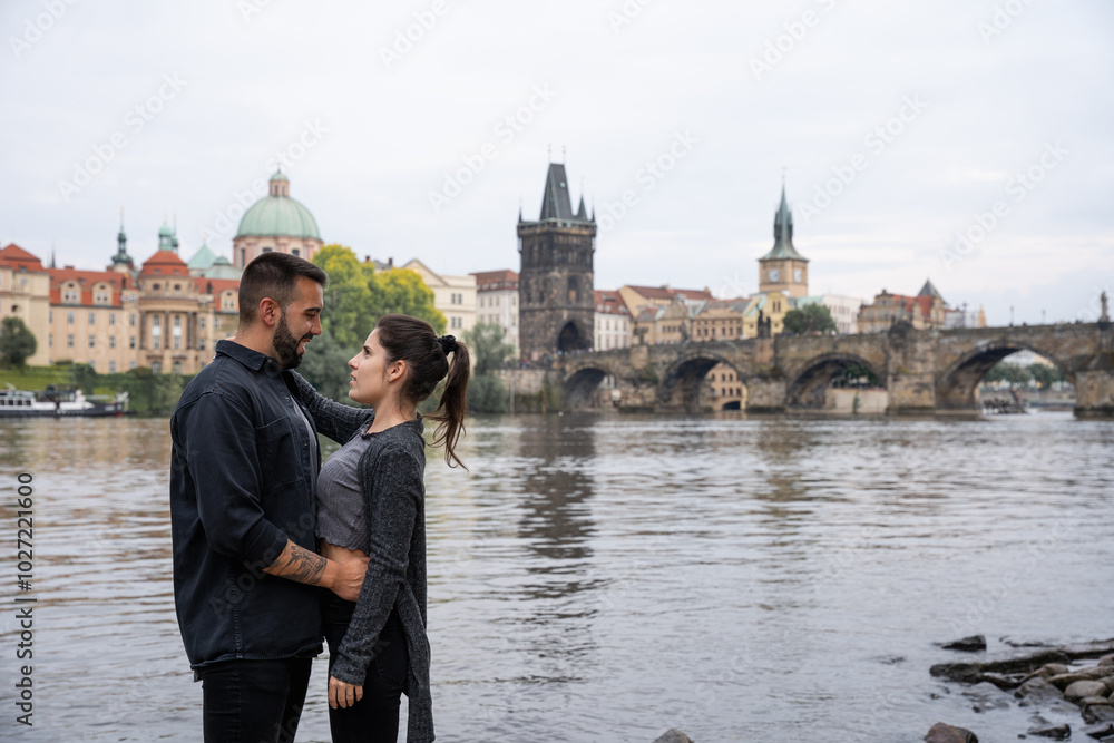 Lovely couple looking at each other, on the river bank and with beautiful views of Prague. Stock ...