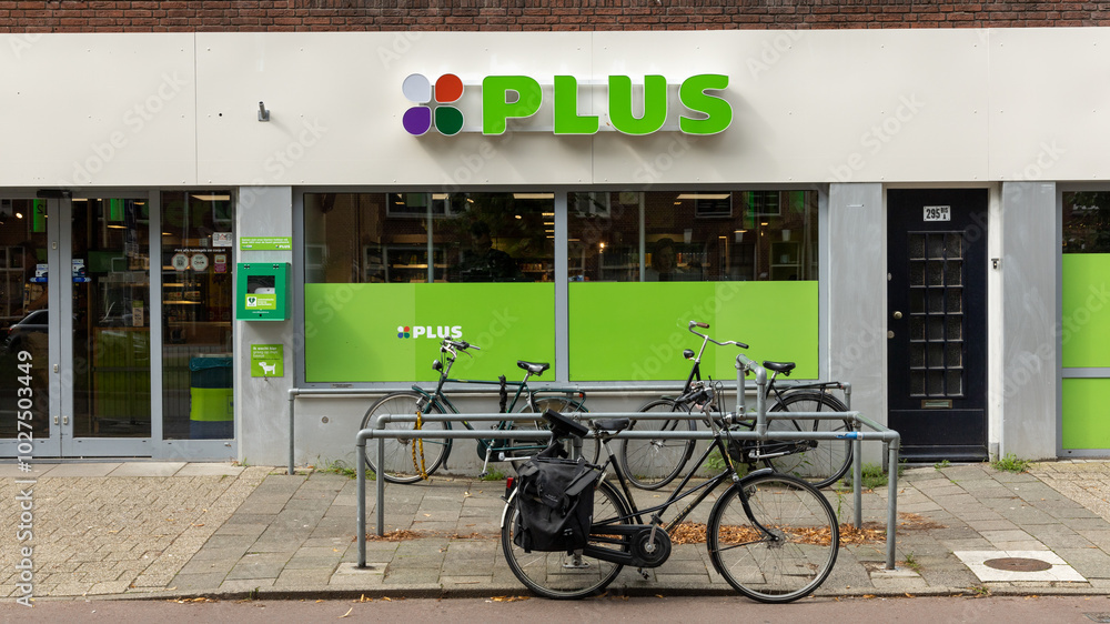 Plus logo sign. Plus is a supermarket groceries store with bikes parked ...