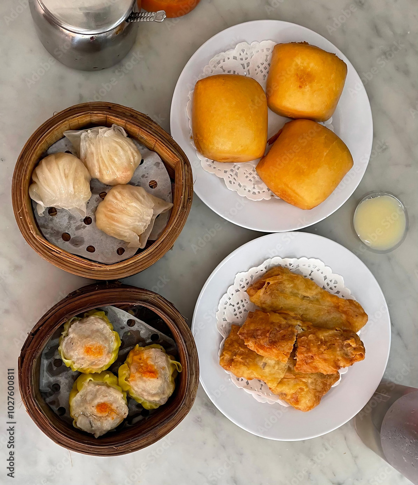 Top-down view of four plates of freshly served dim sum on a marble ...