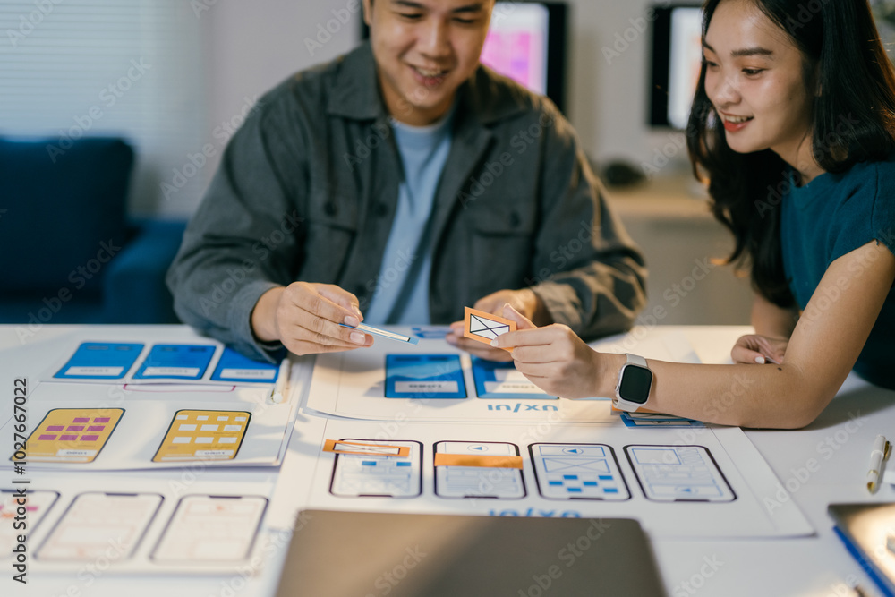 Two asian ui/ux designers are working together in office, holding ui ...