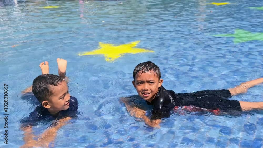 Two Asian little boys playing in the water and relaxing on the edge of ...