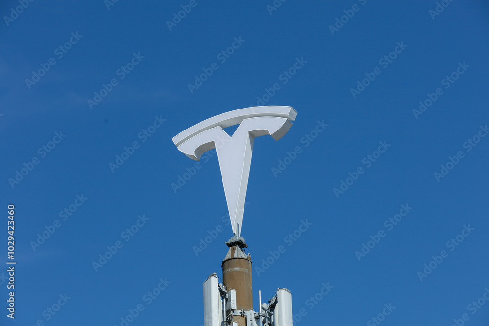 Tesla logo sign on a pole high in the blue sky. Utrecht in the ...