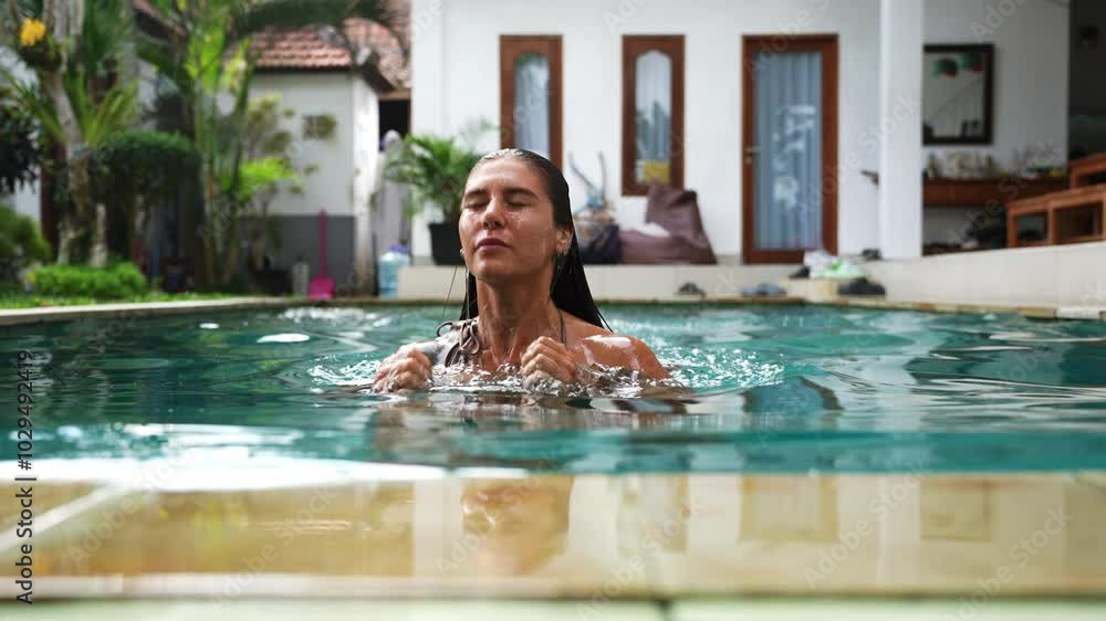 Woman enjoy swim in the pool on backyard her Villa. Relax time during ...
