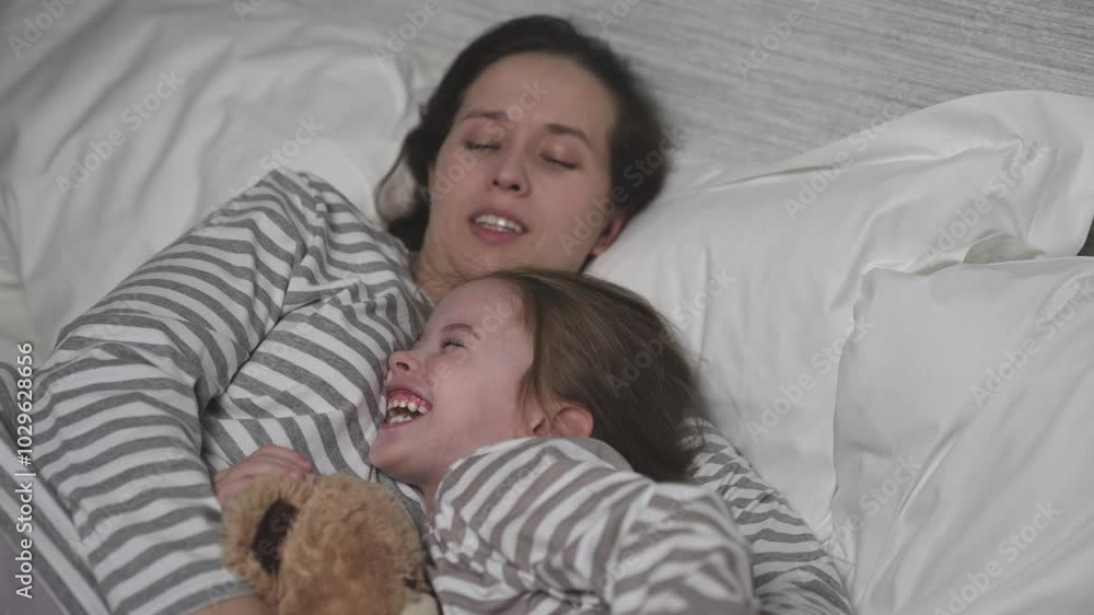 Little child girl fools around and smiles joyfully not letting mother ...
