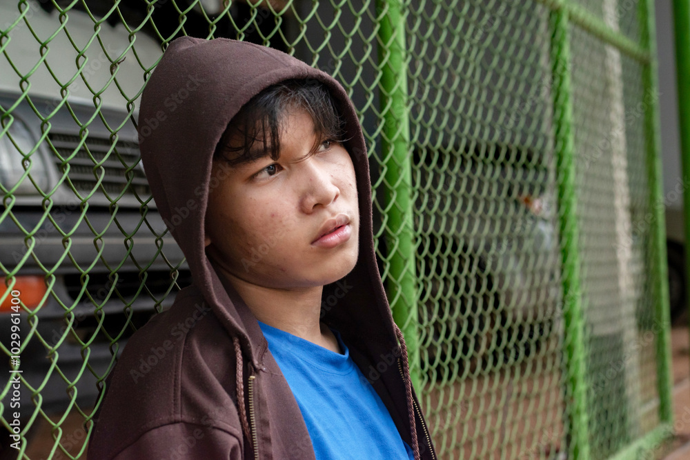Portrait of Asian teenage prisoner behind metal bars in prison cell ...