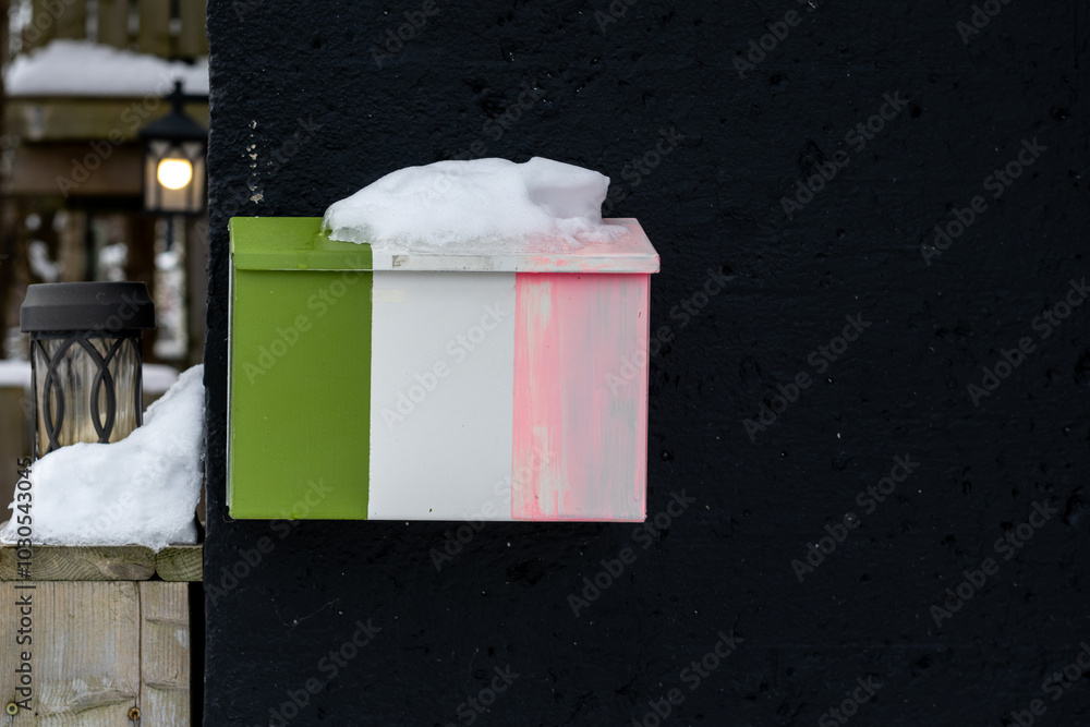 A vibrant green, white, and pink colored mailbox is attached to the ...