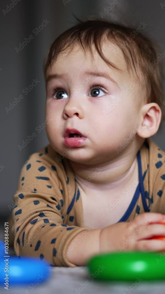 Adorable baby boy lies on the floor looking up with surprise. Child ...