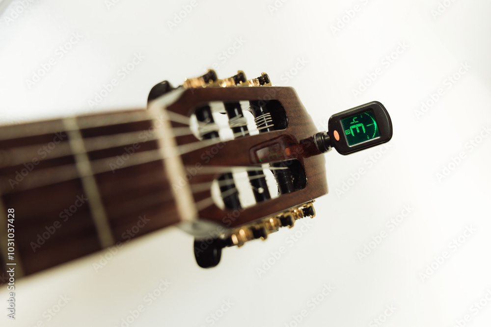 tuning an acoustic guitar using a tuner. close-up. isolated on white ...