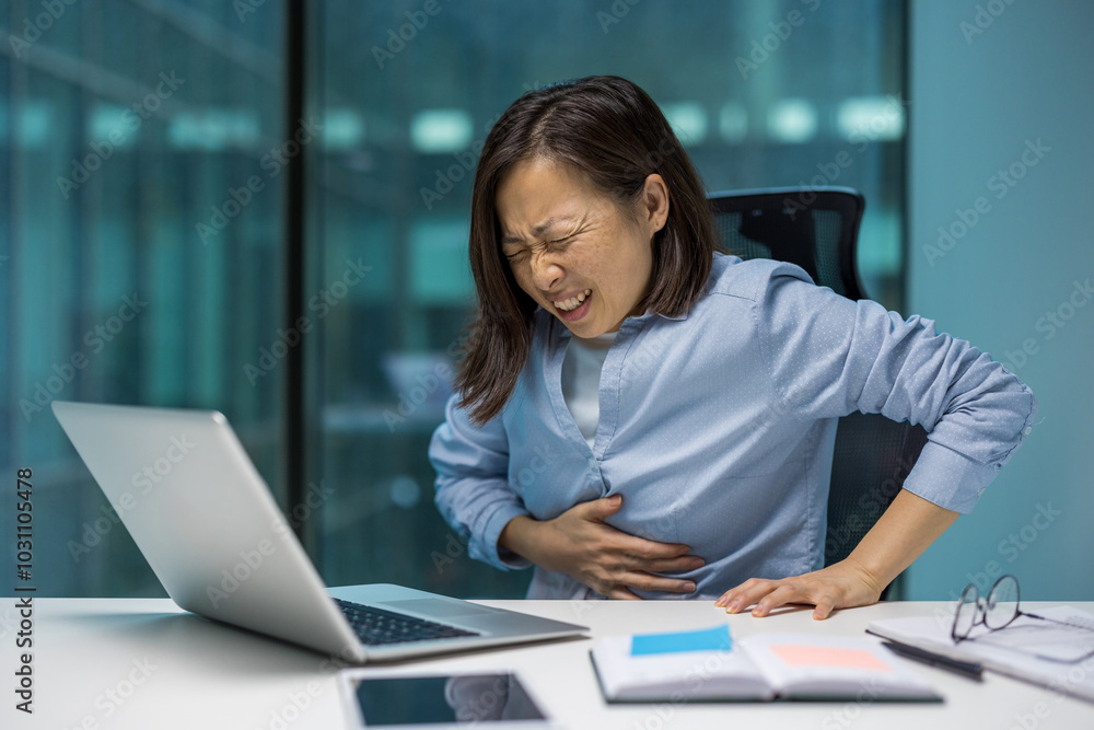 Asian businesswoman showing discomfort from stomach pain while seated ...