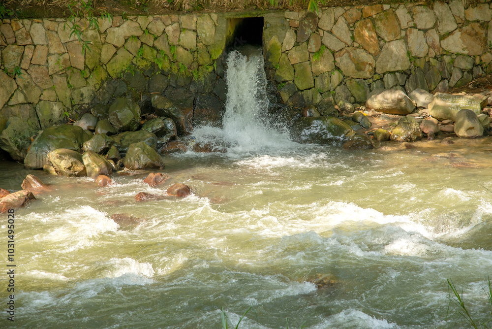Wastewater outlet pipe falling into a river, drain pipe into the river, water flowing from a ...